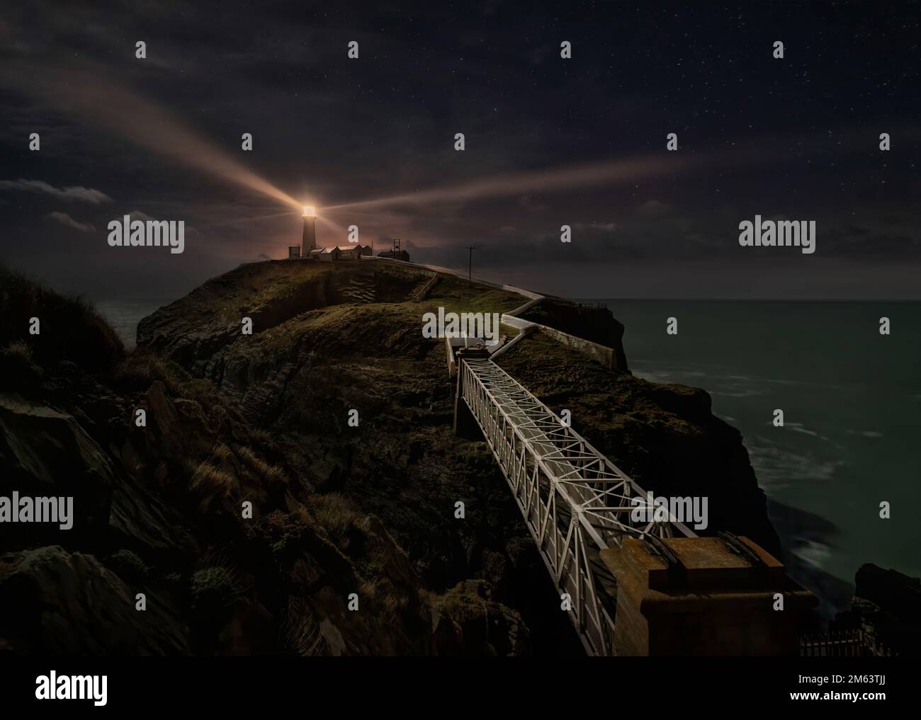 lighthouse at night with beams of light. Perched on a rocky outcrop ...