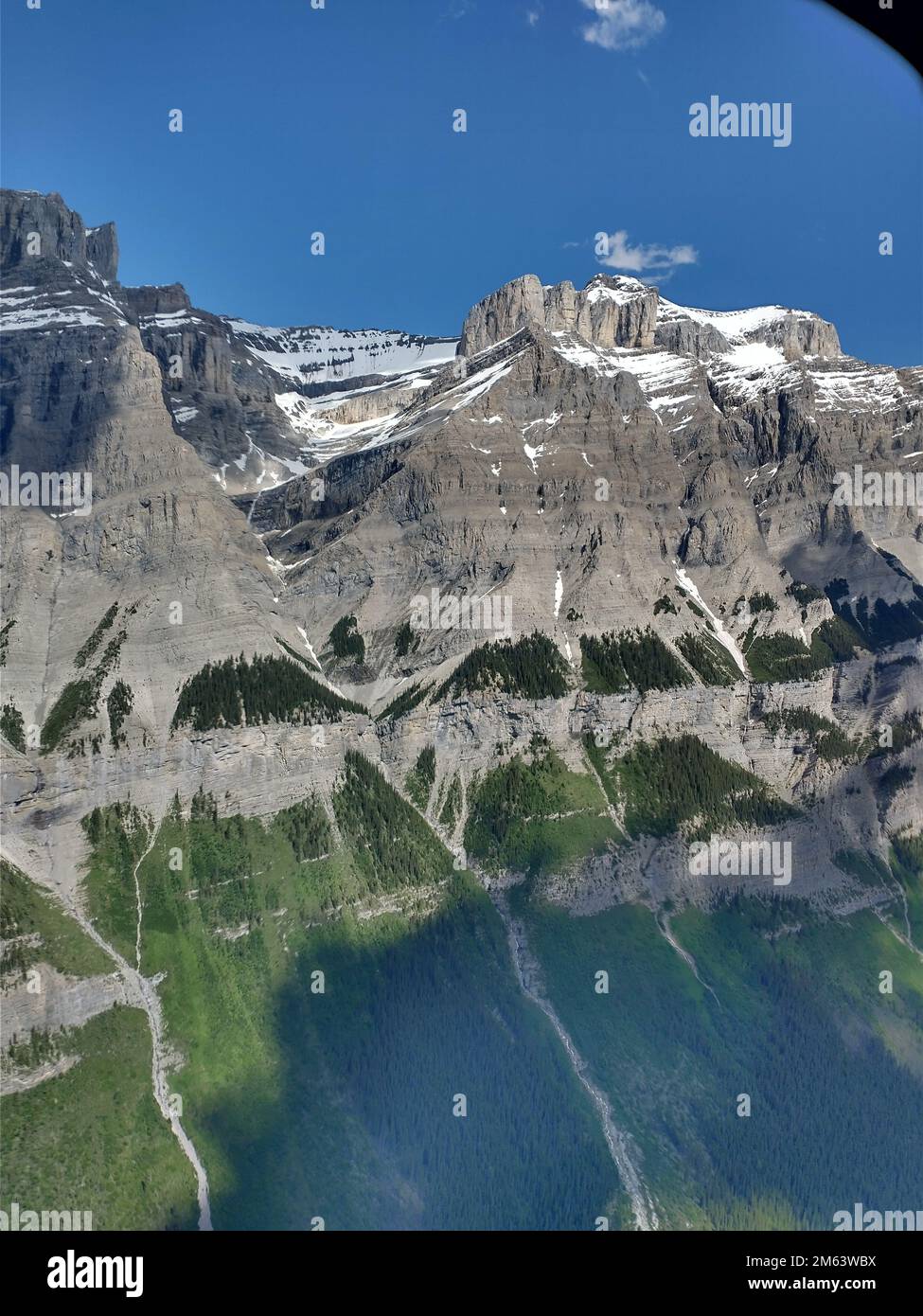 A vertical shot of the Ha Ling Peak under a blue sky in Alberta, Canada ...