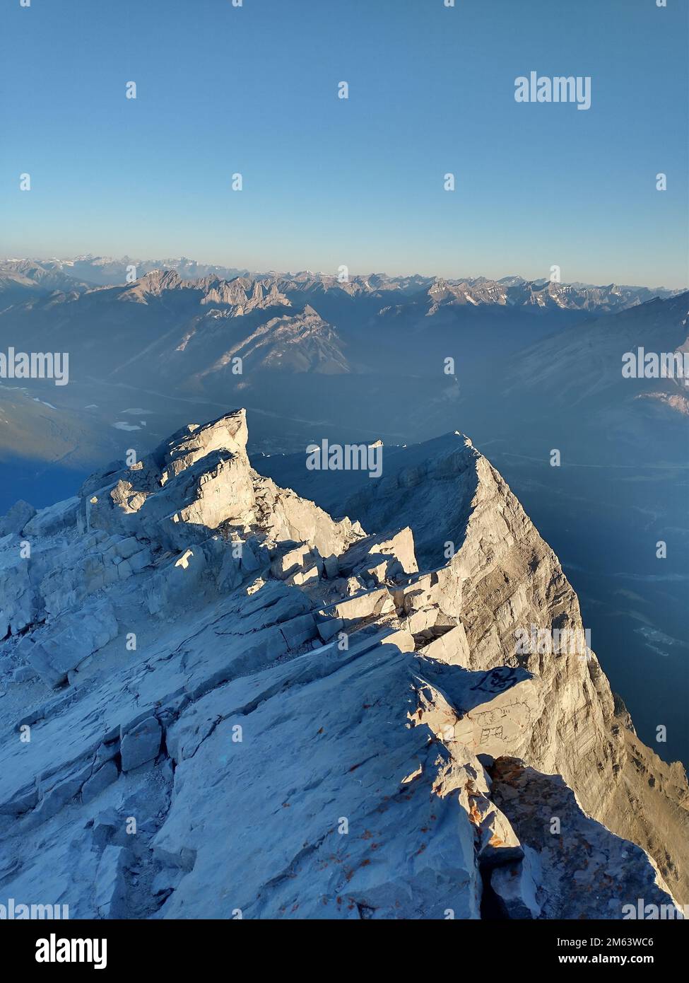 An aerial vertical shot of a mountain peak under a blue sky in Alberta ...