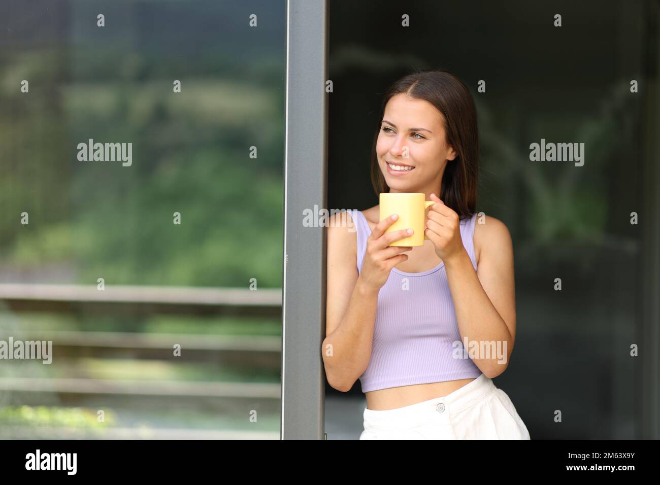 Happy teen drinking coffee leaning in a window looking away Stock Photo ...