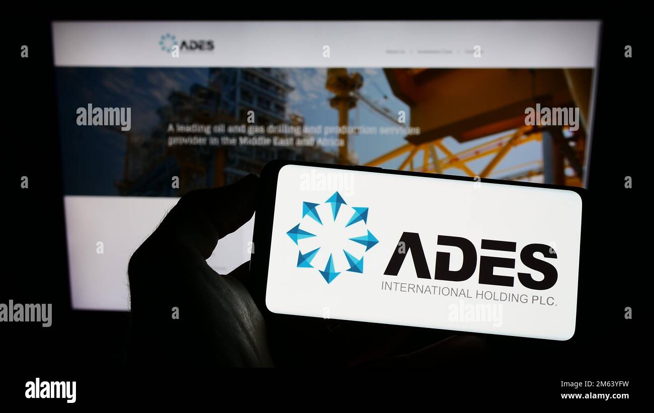 Person holding mobile phone with logo of Egyptian company ADES ...