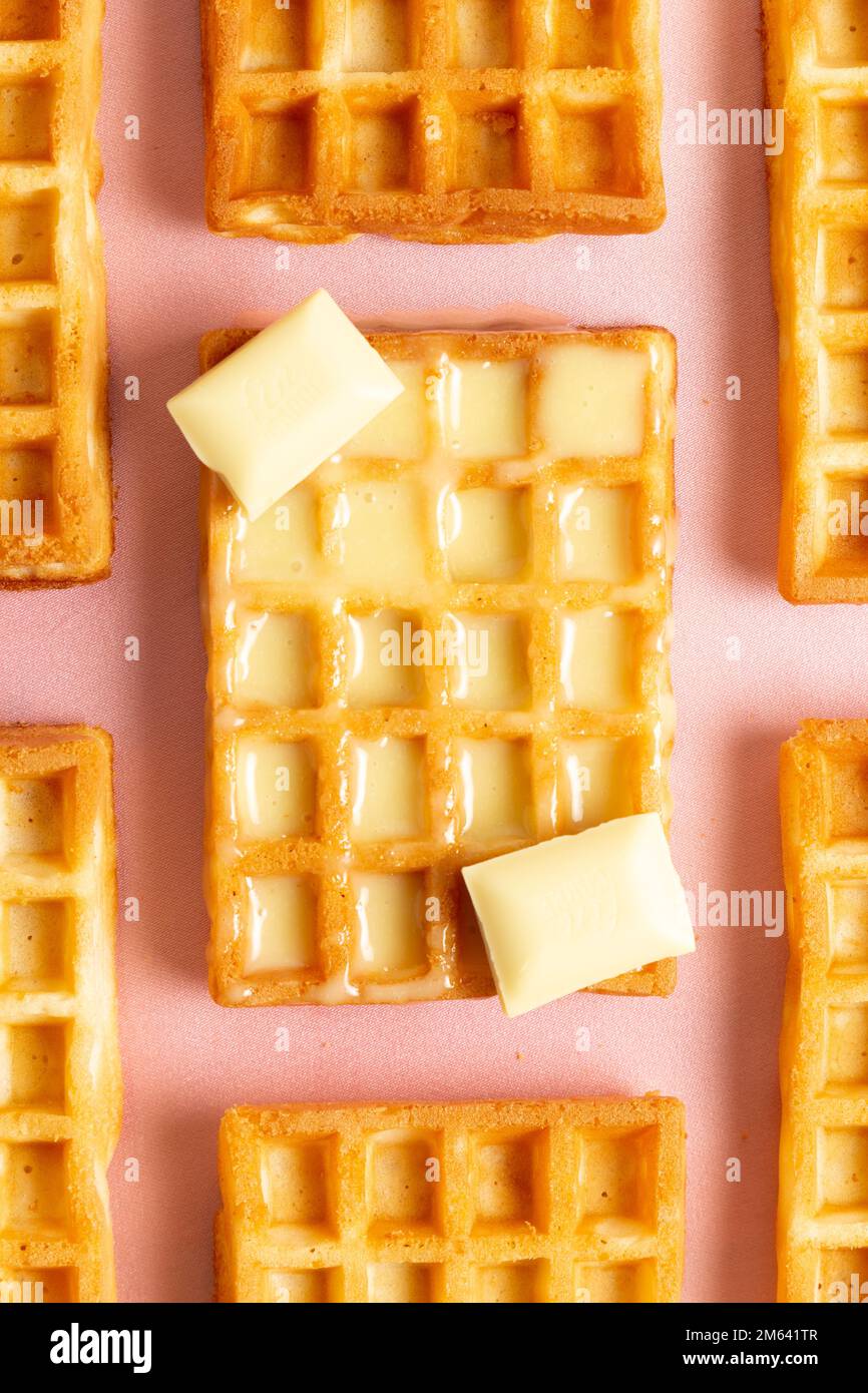 Top vertical view of belgian waffles with white chocolate on a pink ...