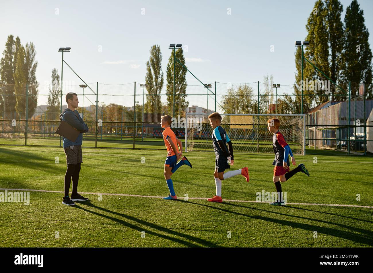 Kids practicing soccer on grass field under football coach control ...