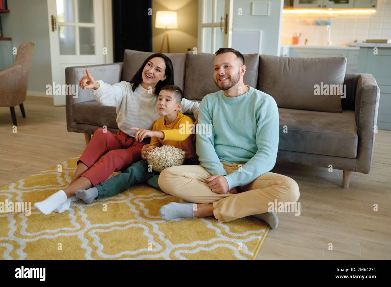 Amazed parents and curious kid watching tv program at home Stock Photo ...