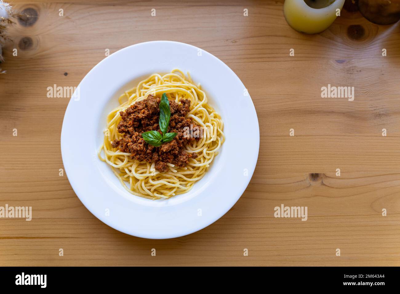 Spaghetti bolognese in a white plate, decorated with basil leaf on a ...