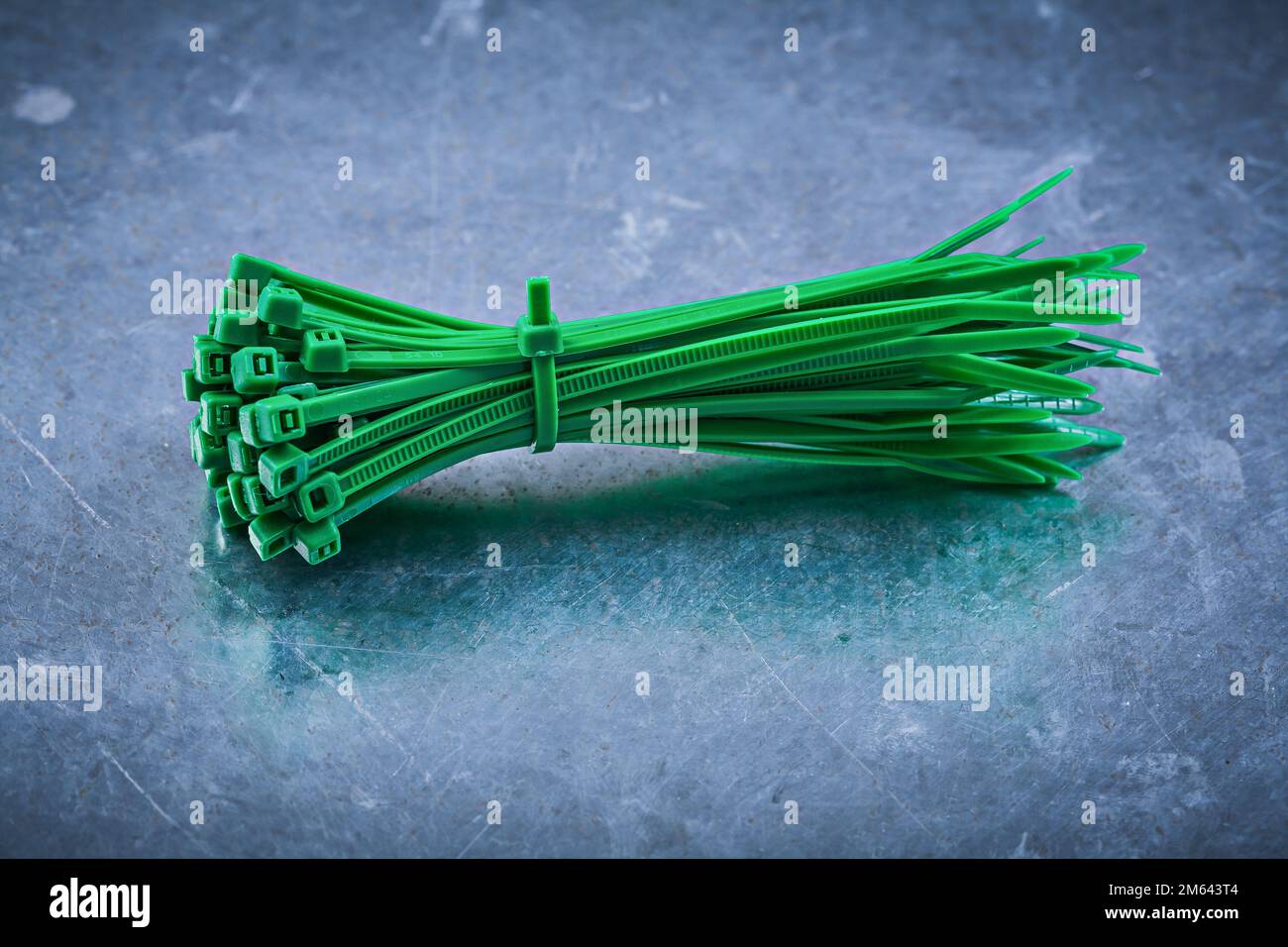 Green plastic self-locking cable ties on metallic background ...