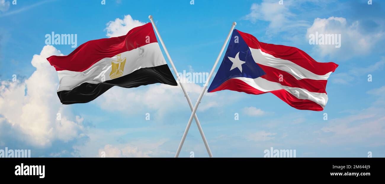 two crossed flags Puerto Rico and Egypt waving in wind at cloudy sky. Concept of relationship ...