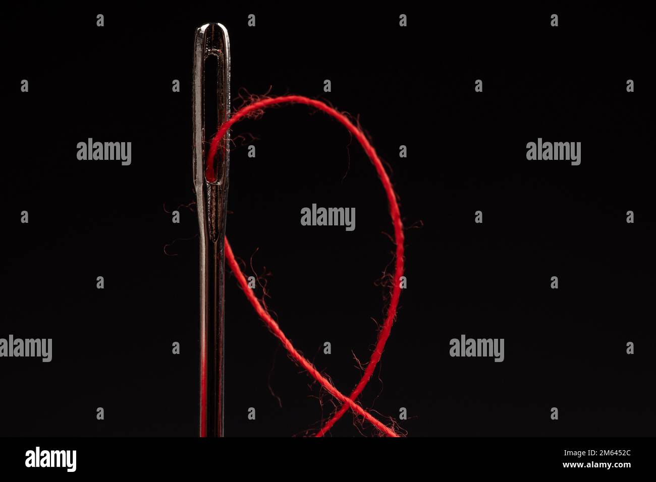 Red thread and needle on black background Stock Photo - Alamy