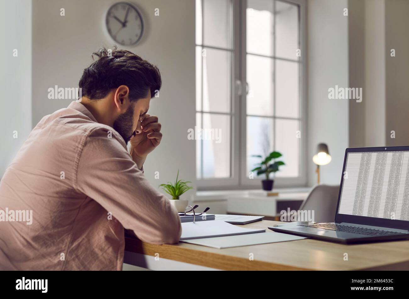 Tired, stressed man with a headache sitting at his office desk with a ...