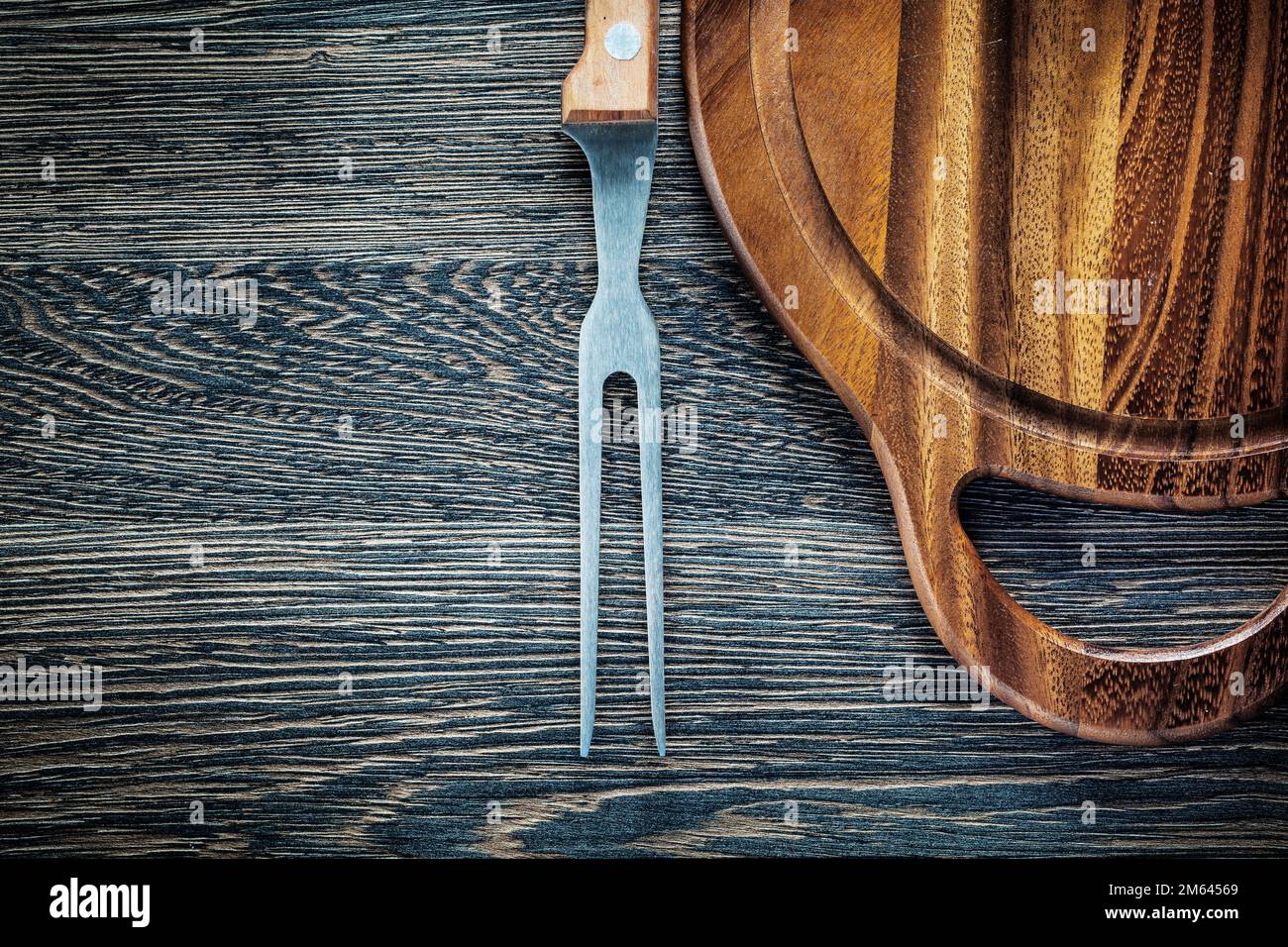 Meat fork carving board on wood background Stock Photo - Alamy