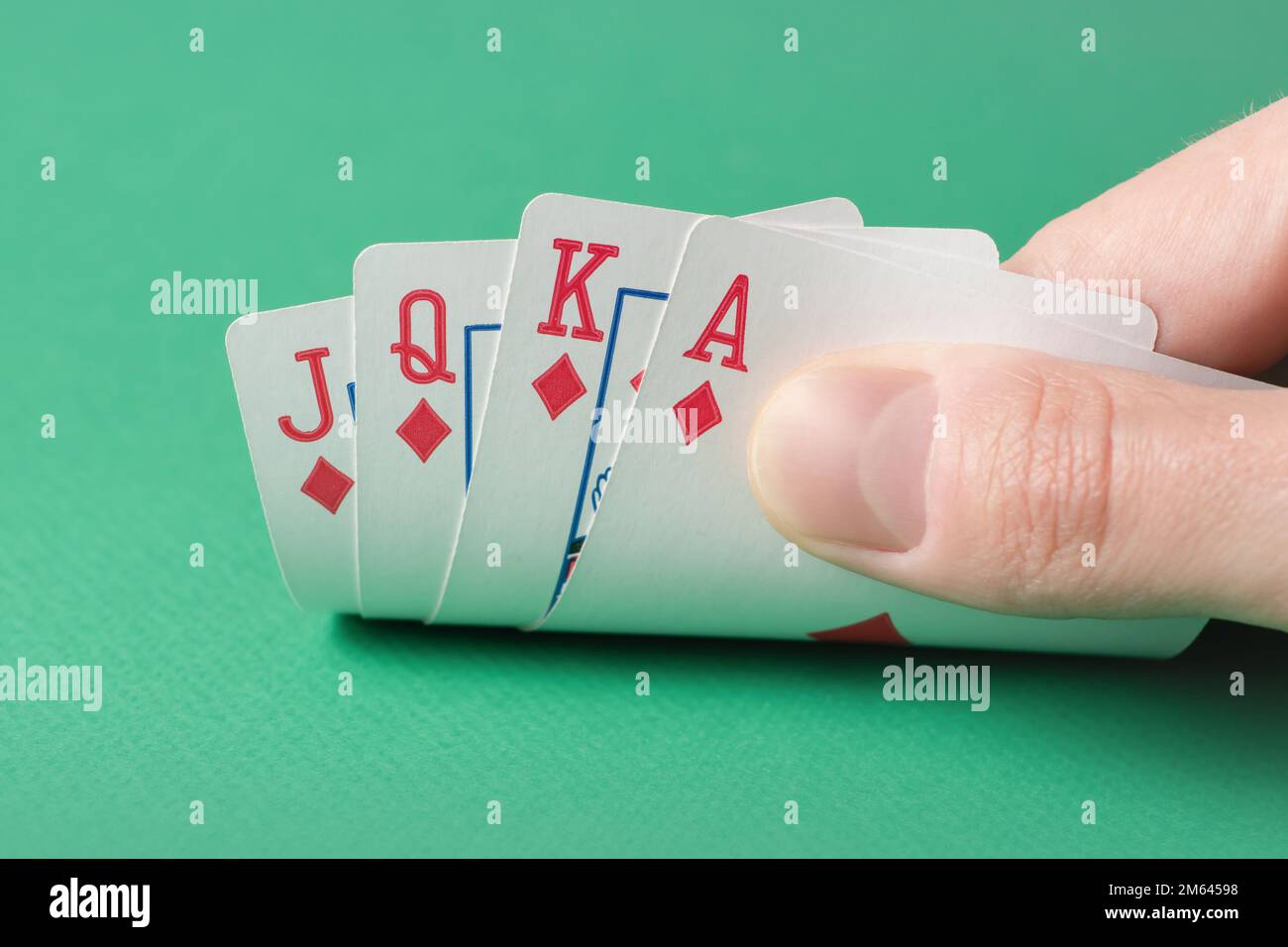 Playing cards in hand on green background Stock Photo - Alamy
