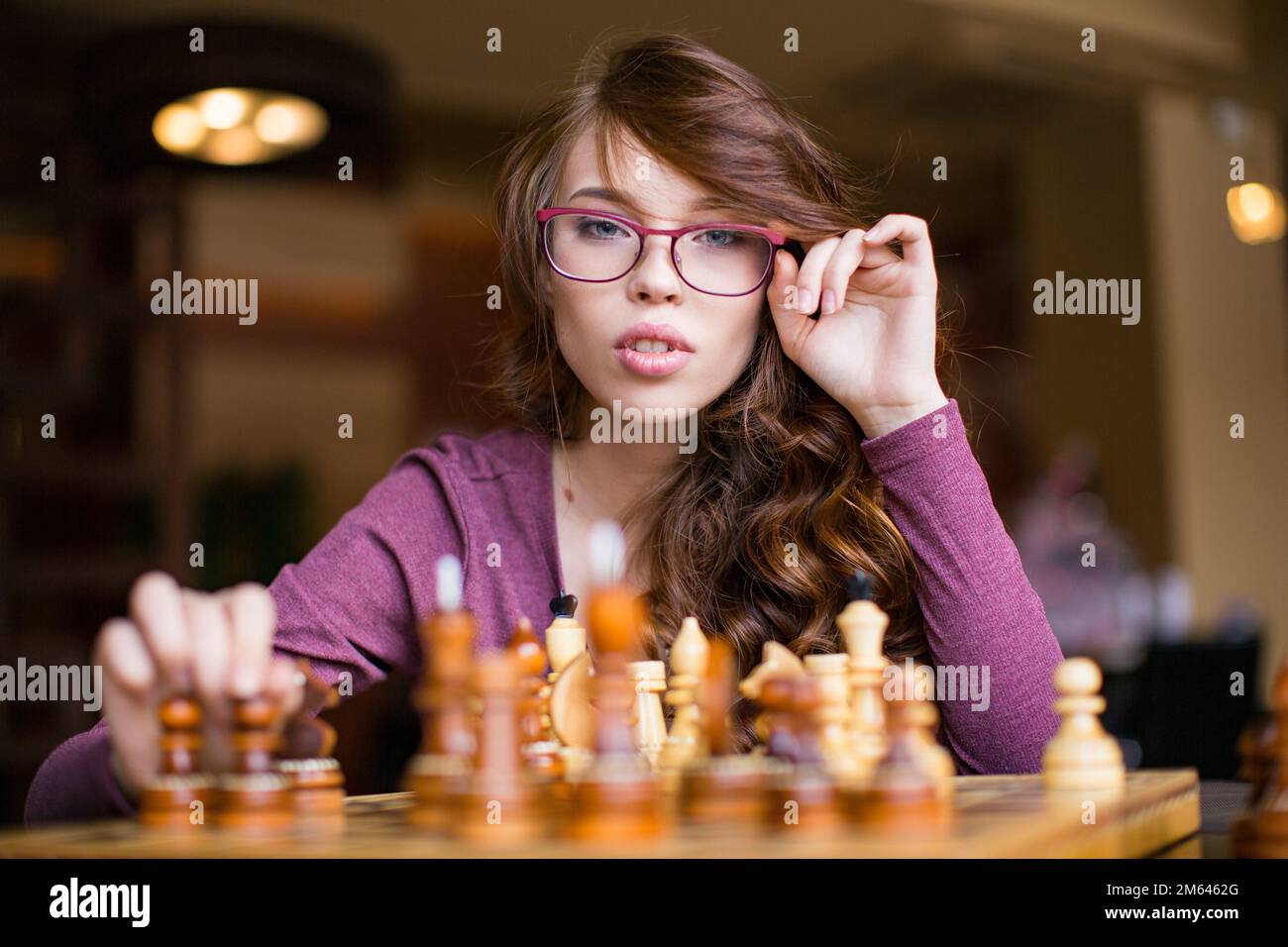 Woman playing chess indoor and thinking position, find winning move ...