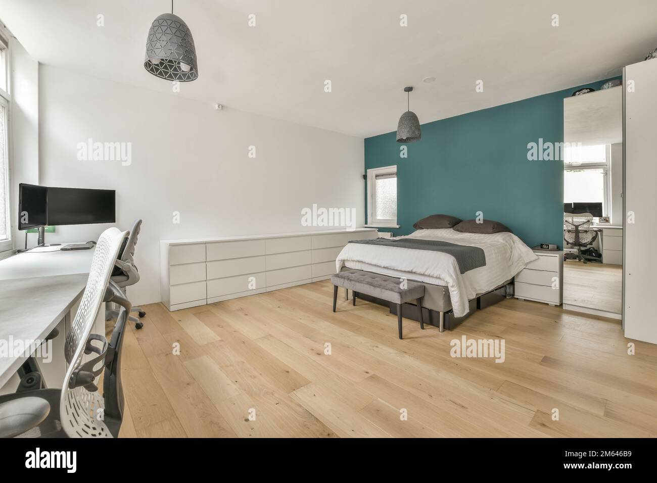 a bedroom with a bed, desk and computer monitor on the wall in front of ...