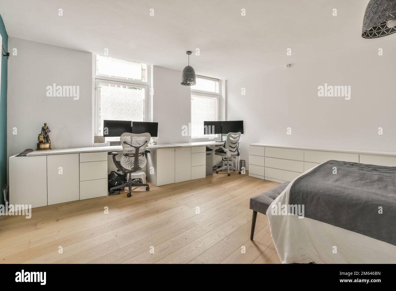 a bedroom with a bed, desk and computer monitor on the wall in front of ...