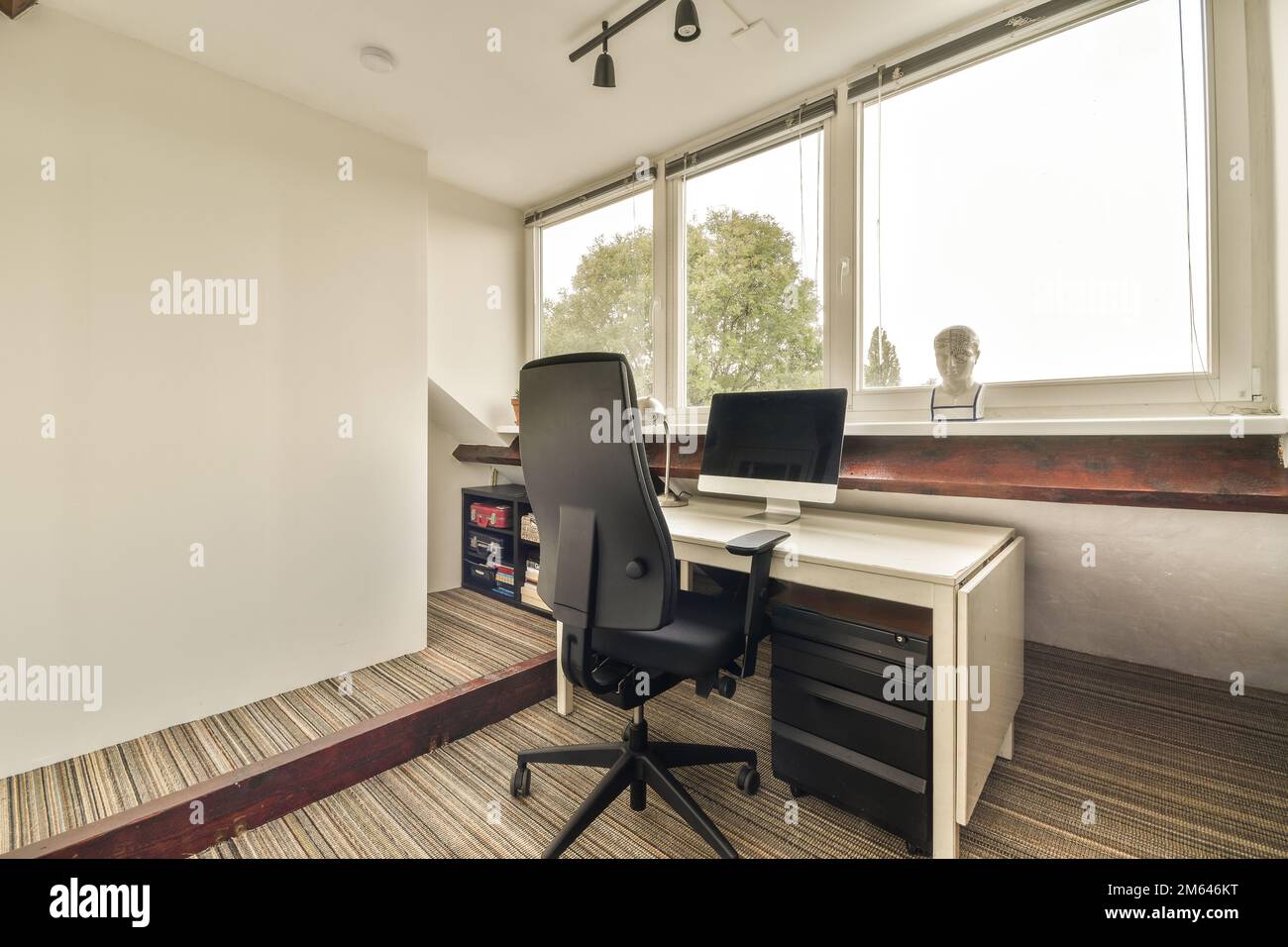 an office area with a desk, chair and computer monitor on the wall in ...