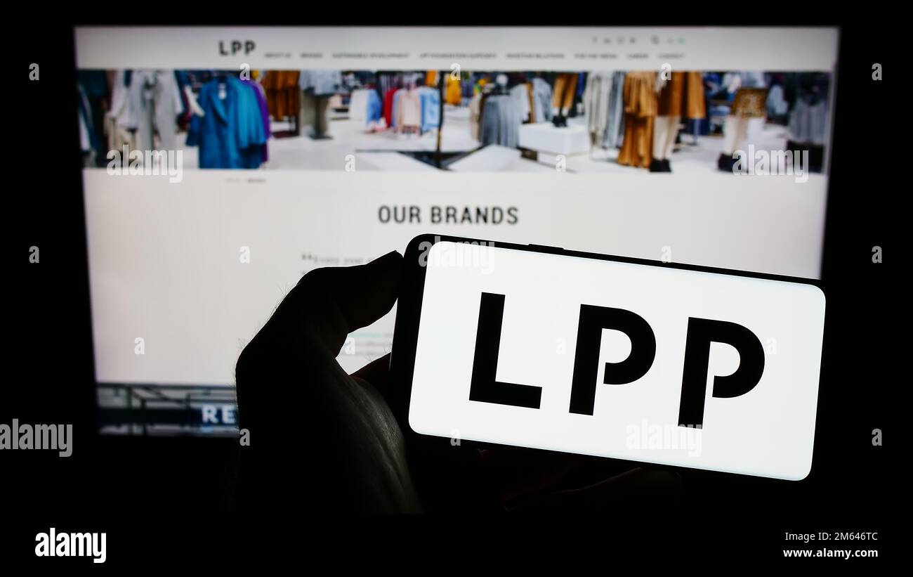 Person holding cellphone with logo of Polish clothing retail company LPP S.A. on screen in front ...
