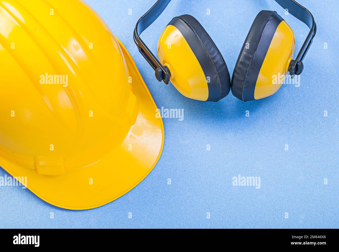 Safety earmuffs building helmet on blue background construction concept ...