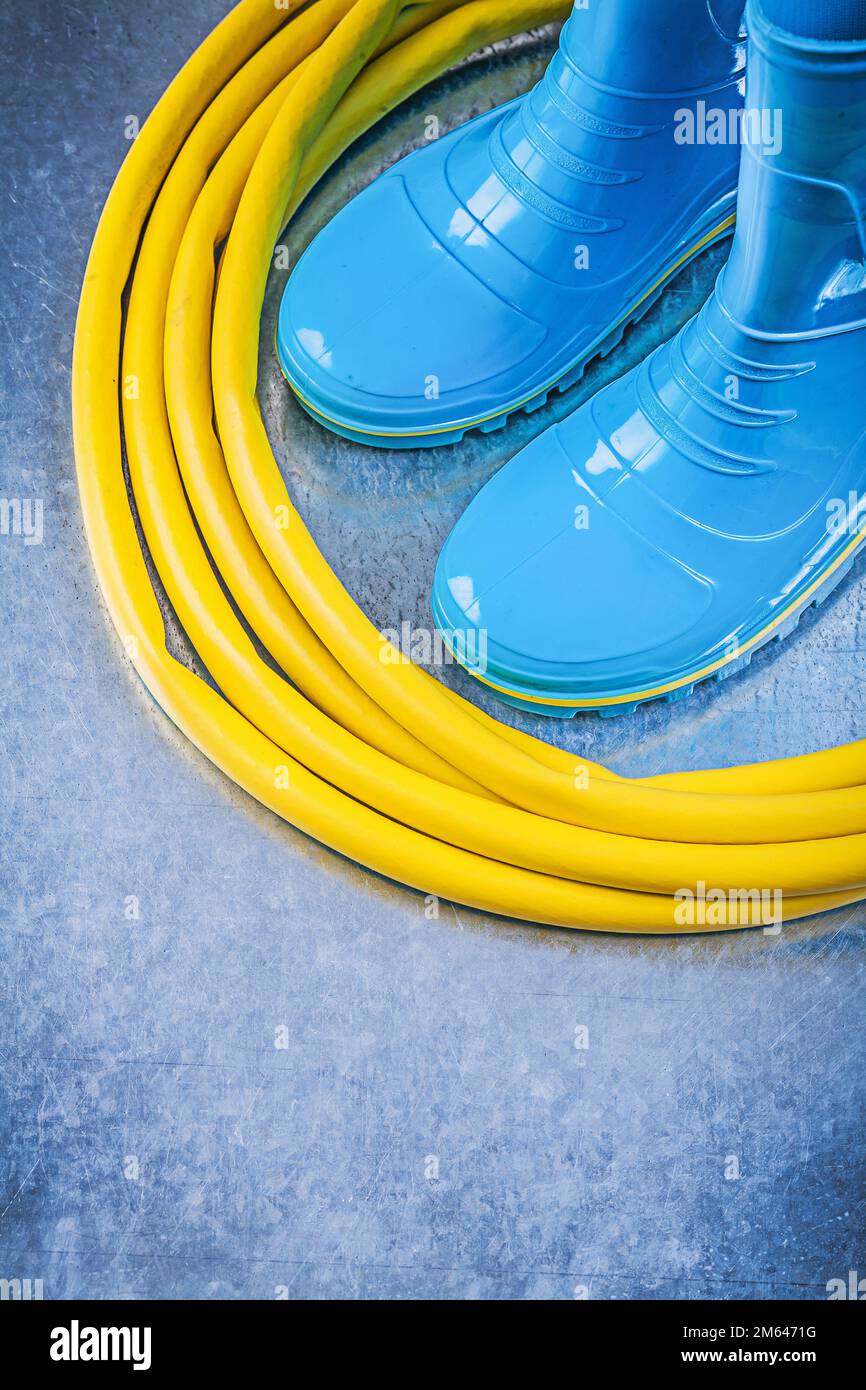 Safety rubber boots garden hose on metallic background gardening ...