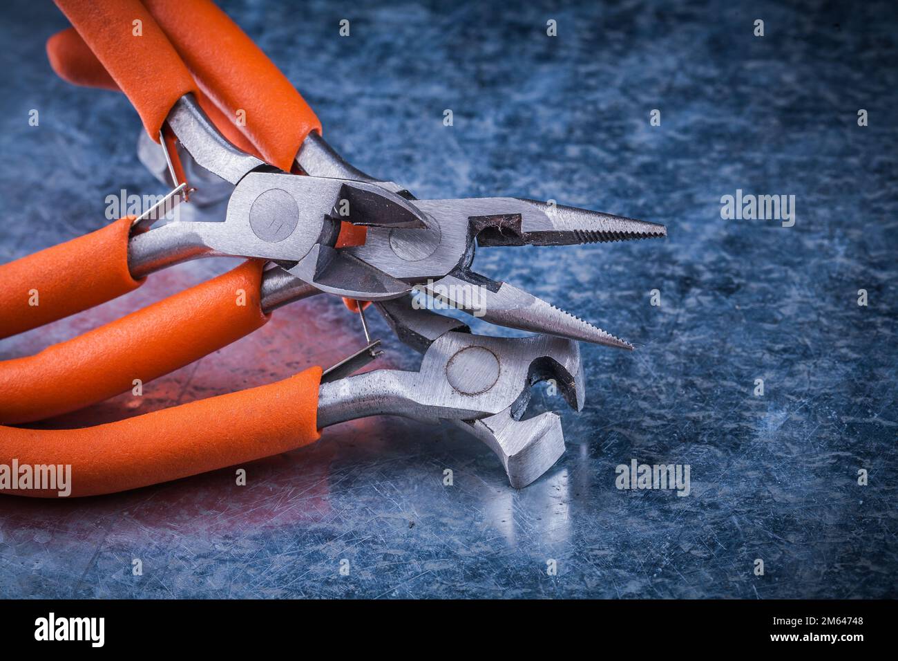 Set of insulated electric pliers nippers on scratched metallic ...