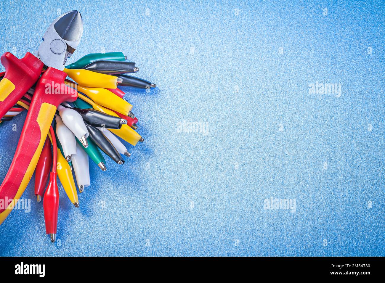 Set of multicolored cable crocodiles cutting pliers on blue background ...