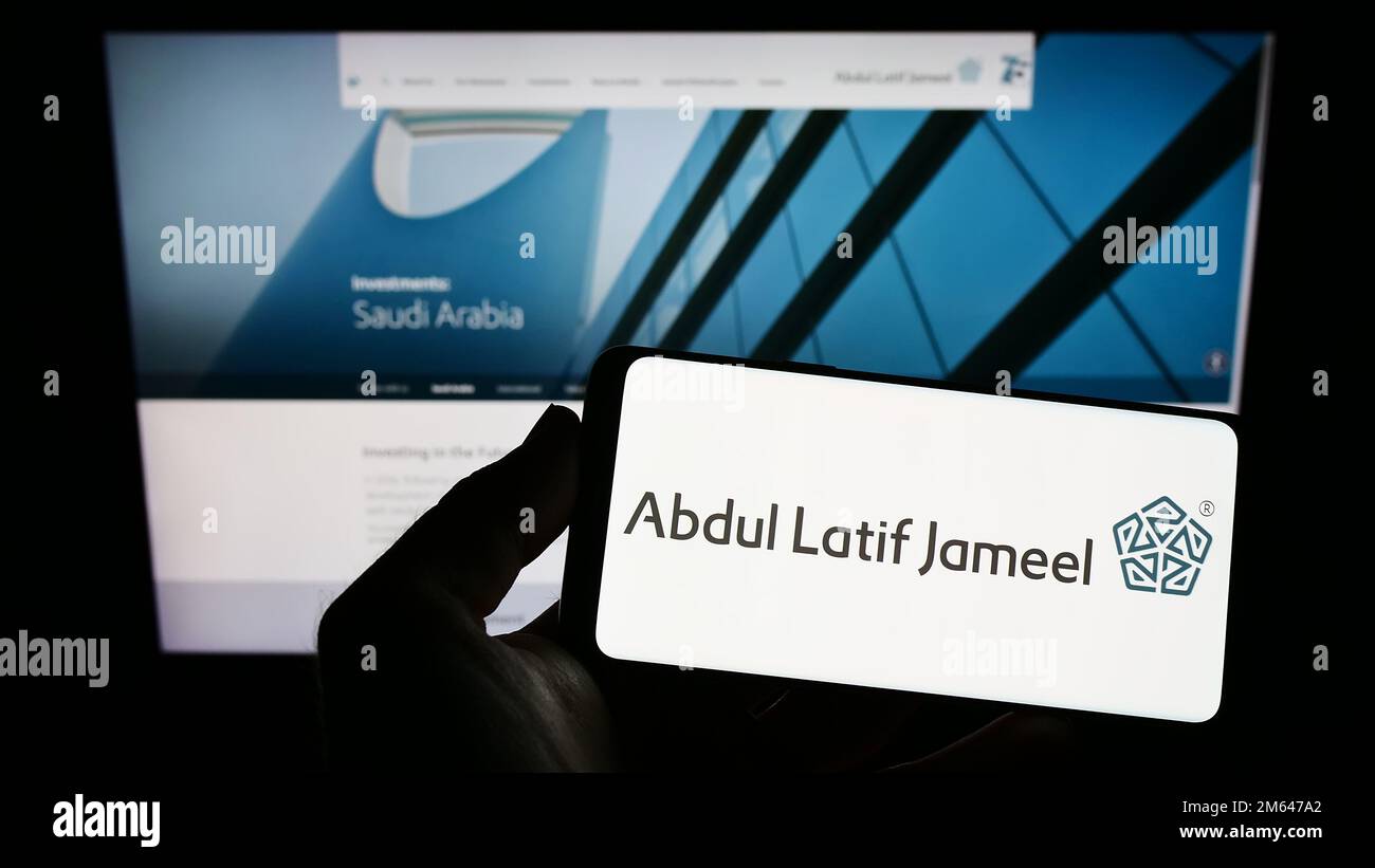 Person holding smartphone with logo of Saudi Arabian company Abdul ...
