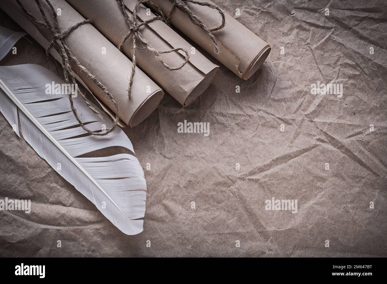 Stack of vintage paper scrolls quill on crumpled wrapping sheet Stock ...