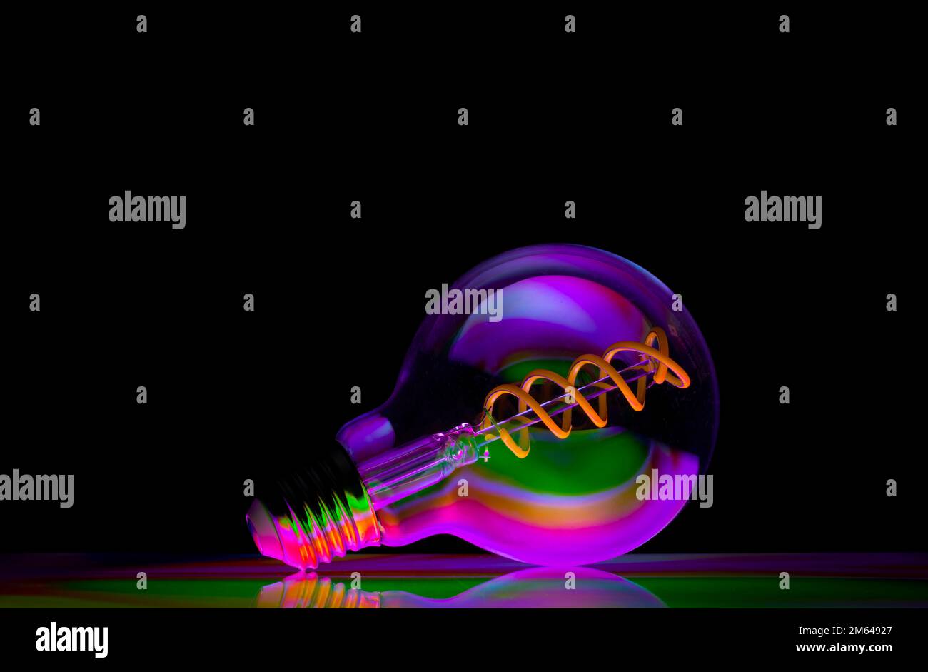 Colourful patterns reflect within a clear glass round shaped lightbulb ...