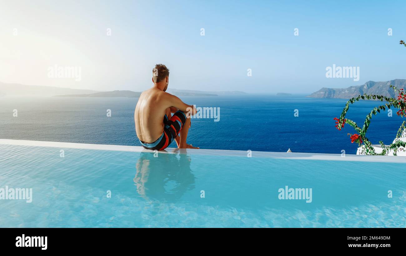 Santorini Greece Oia, young men in swim shorts relaxing in the pool ...
