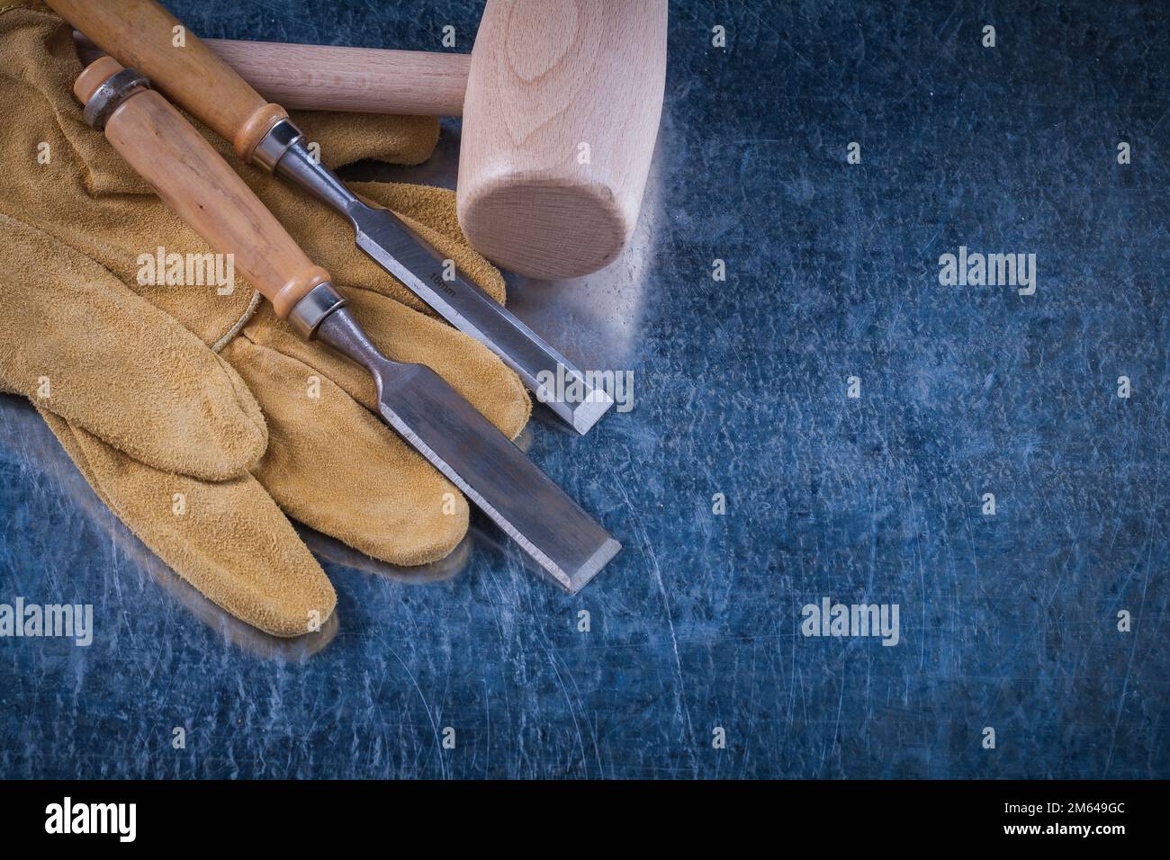 Wooden hammer firmer chisels and leather safety gloves on scratched ...