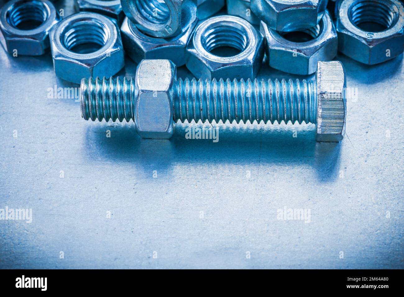 Vertical view of threaded screw nuts and bolts on metallic background ...