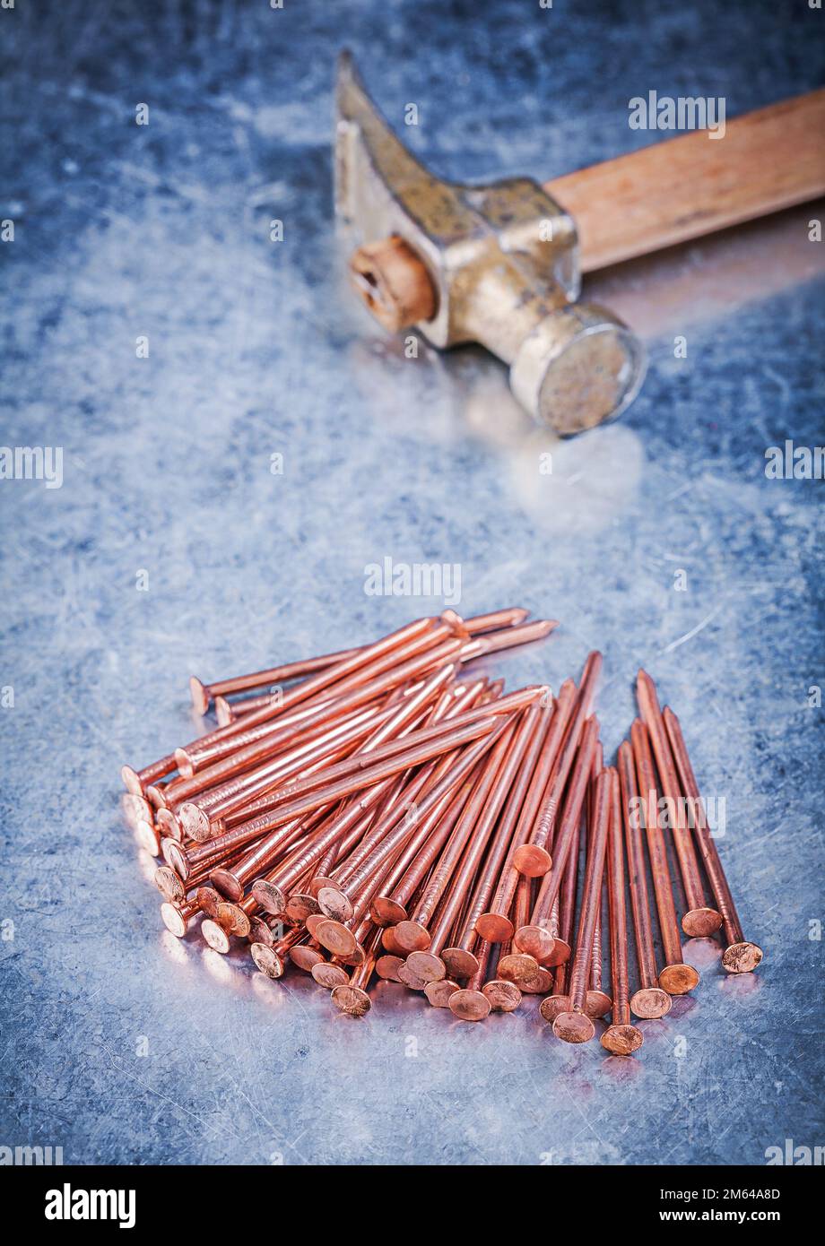 Vintage claw hammer heap of copper construction nails on metallic ...