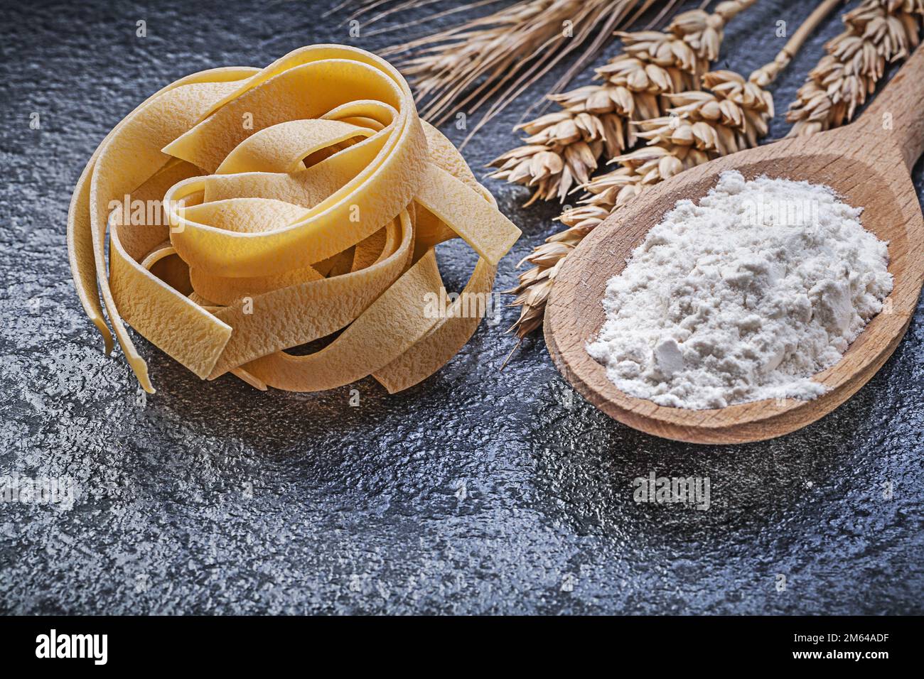 Wheat rye ears wooden spoon flour raw pasta on black background food ...