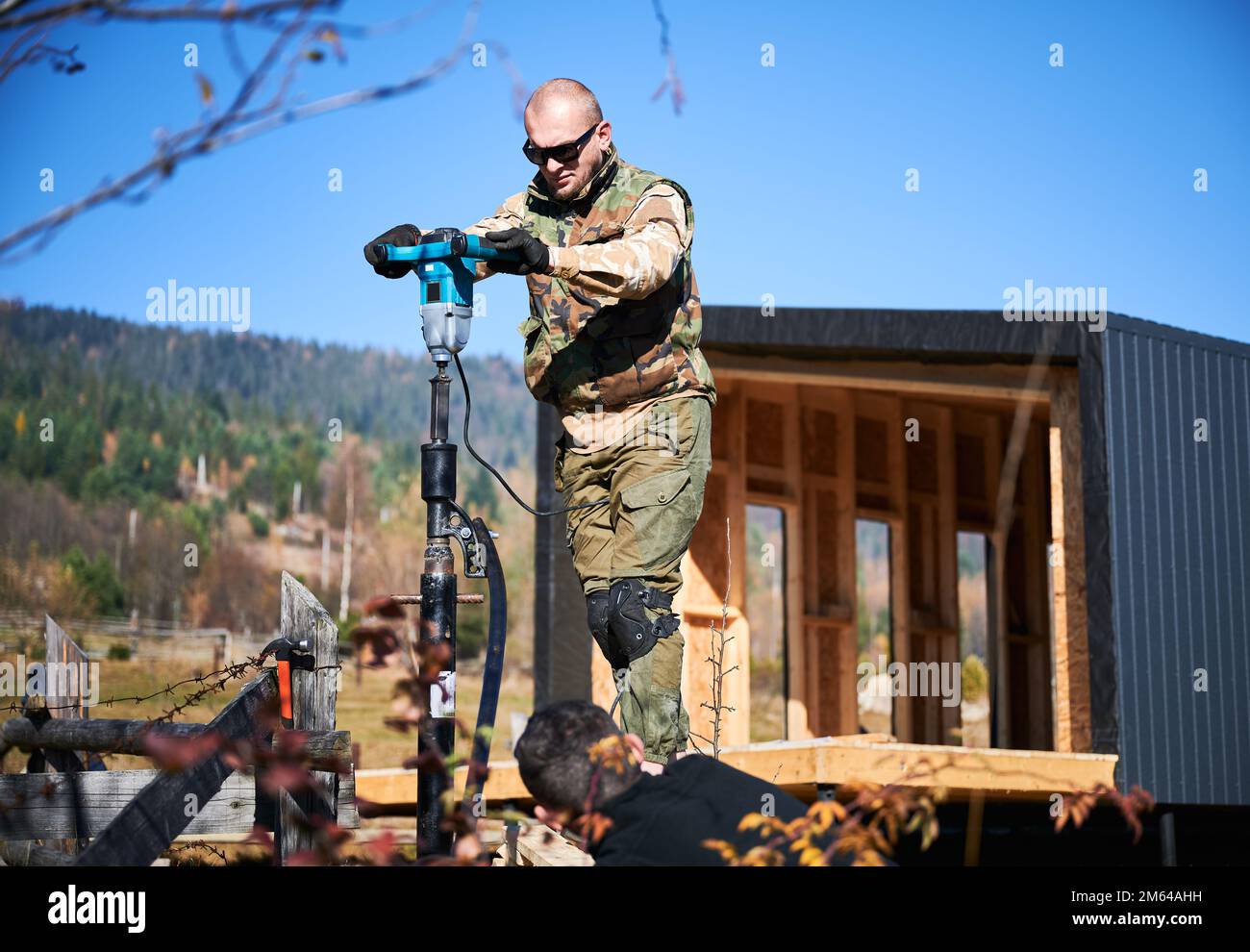 Male workers building pile foundation for wooden frame house. Men ...