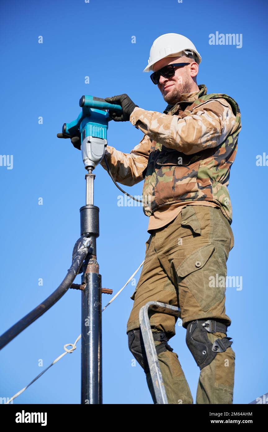 Male worker building pile foundation for wooden frame house. Man ...
