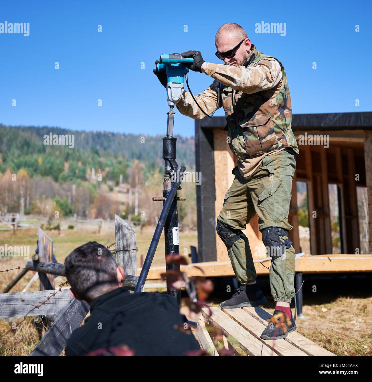 Male workers building pile foundation for wooden frame house. Men ...