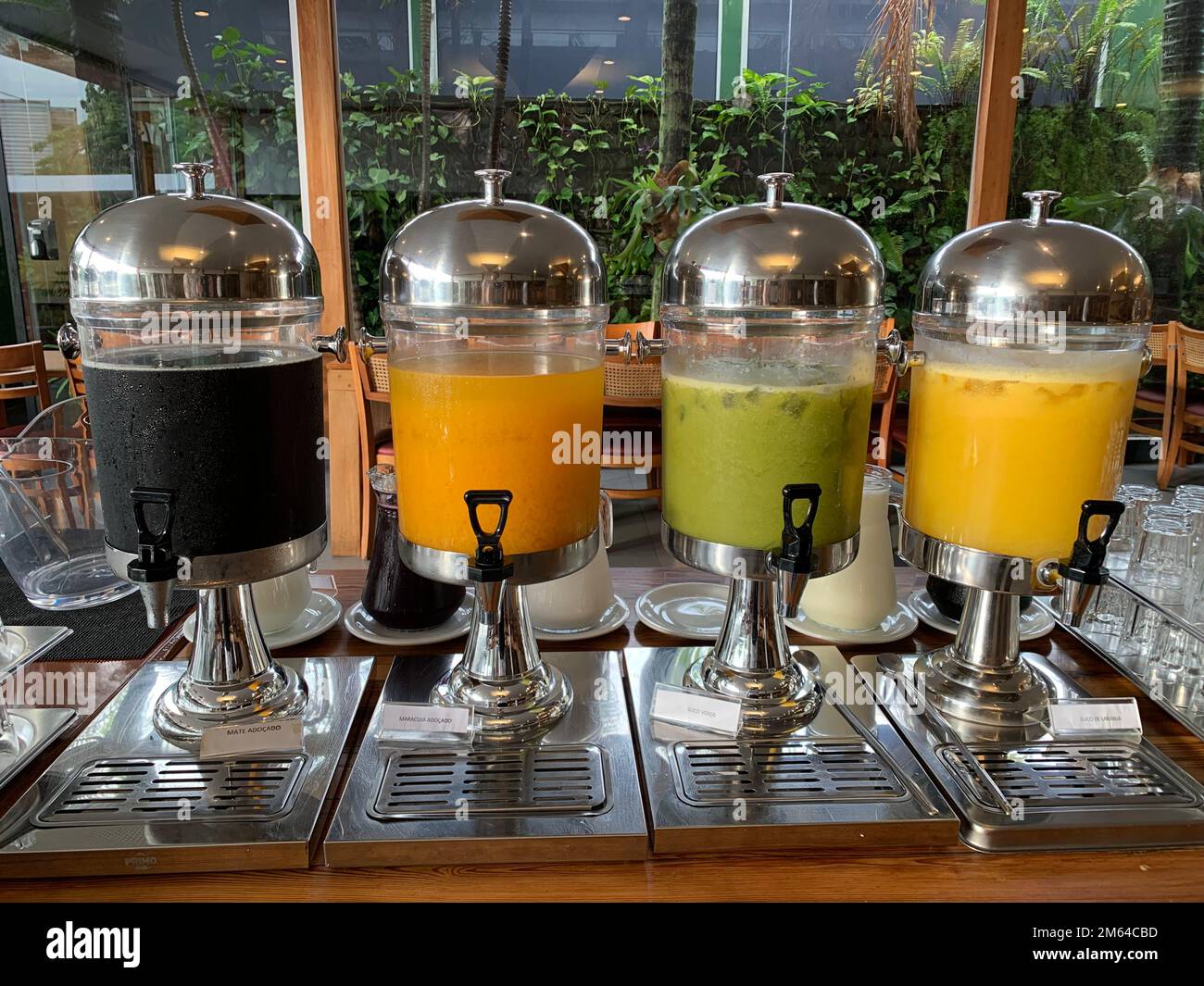 Four transparent juice dispensers with tap filled with colorful juices ...