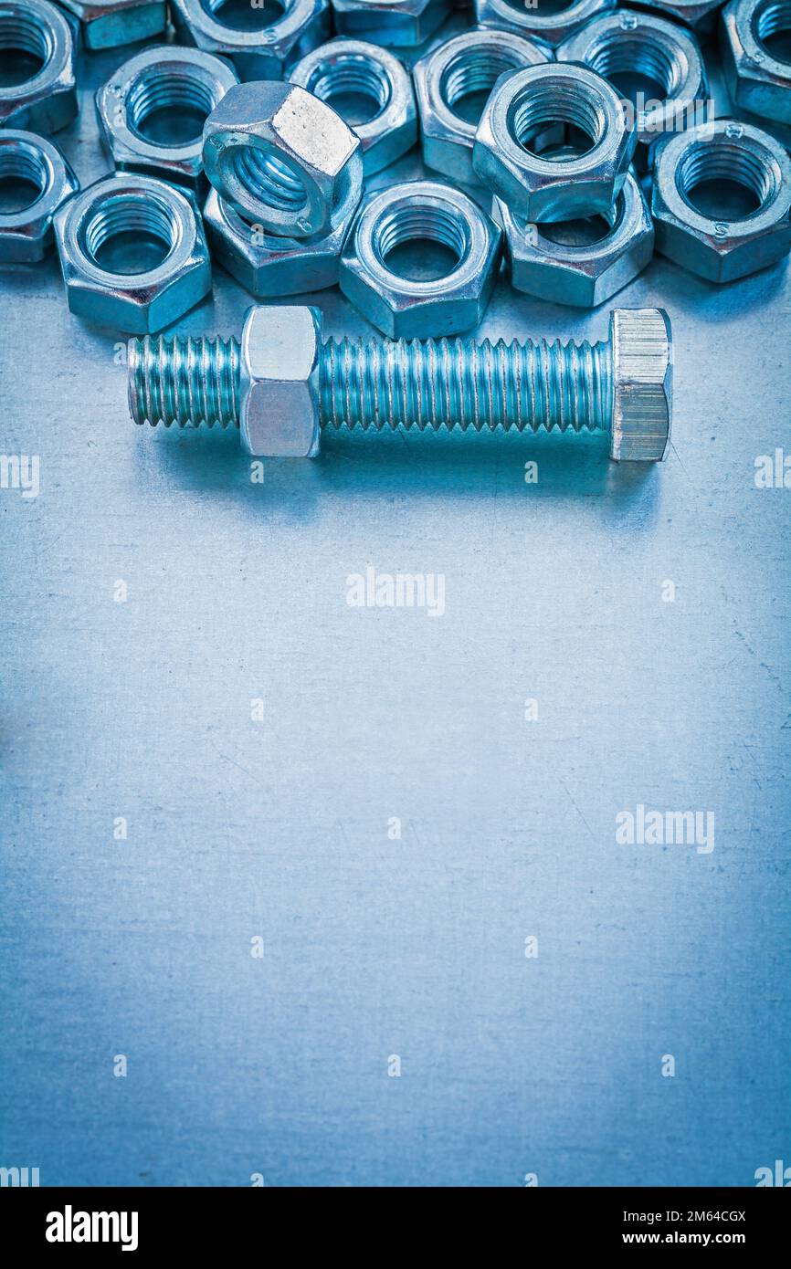 Vertical copyspace image of screw nuts and bolts on metallic background ...