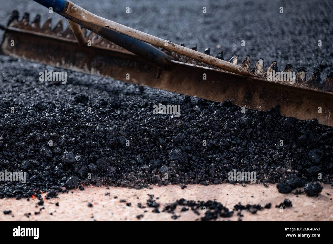An Airman from the 820th RED HORSE Squadron uses an asphalt rake to fix ...