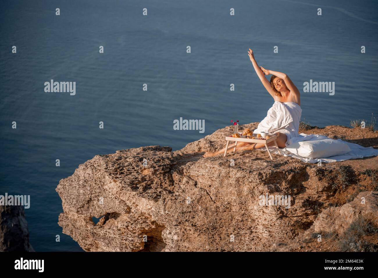 Woman wake up in bed wuth duvet and pillow over nature sea background ...