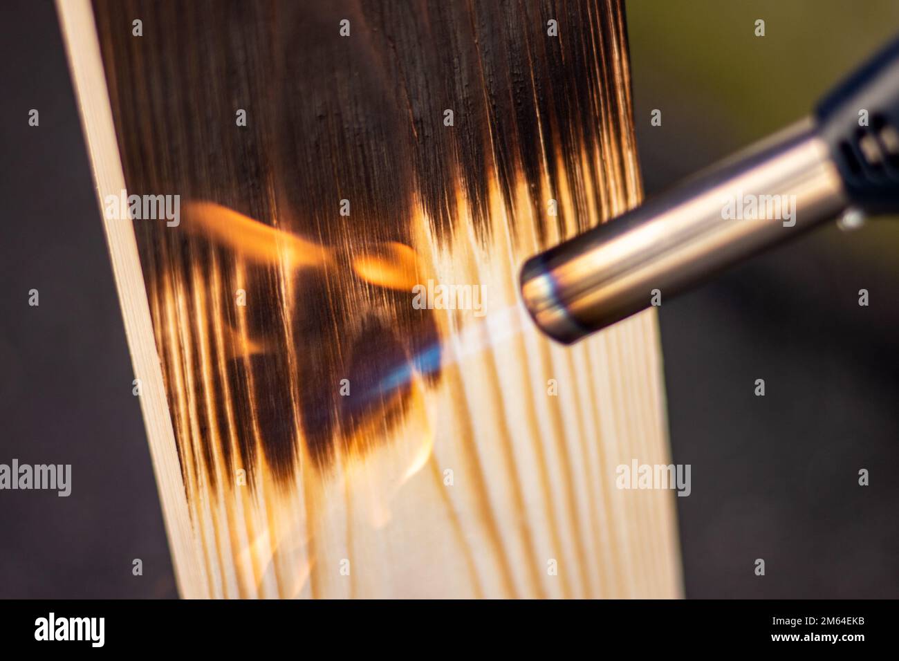 Burning wood with a gas burner on a dark background Stock Photo - Alamy