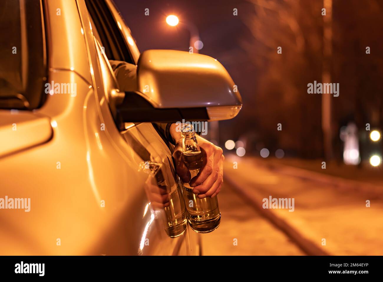 Drunk man driving a car with a bottle of beer at the night. Don't drink ...