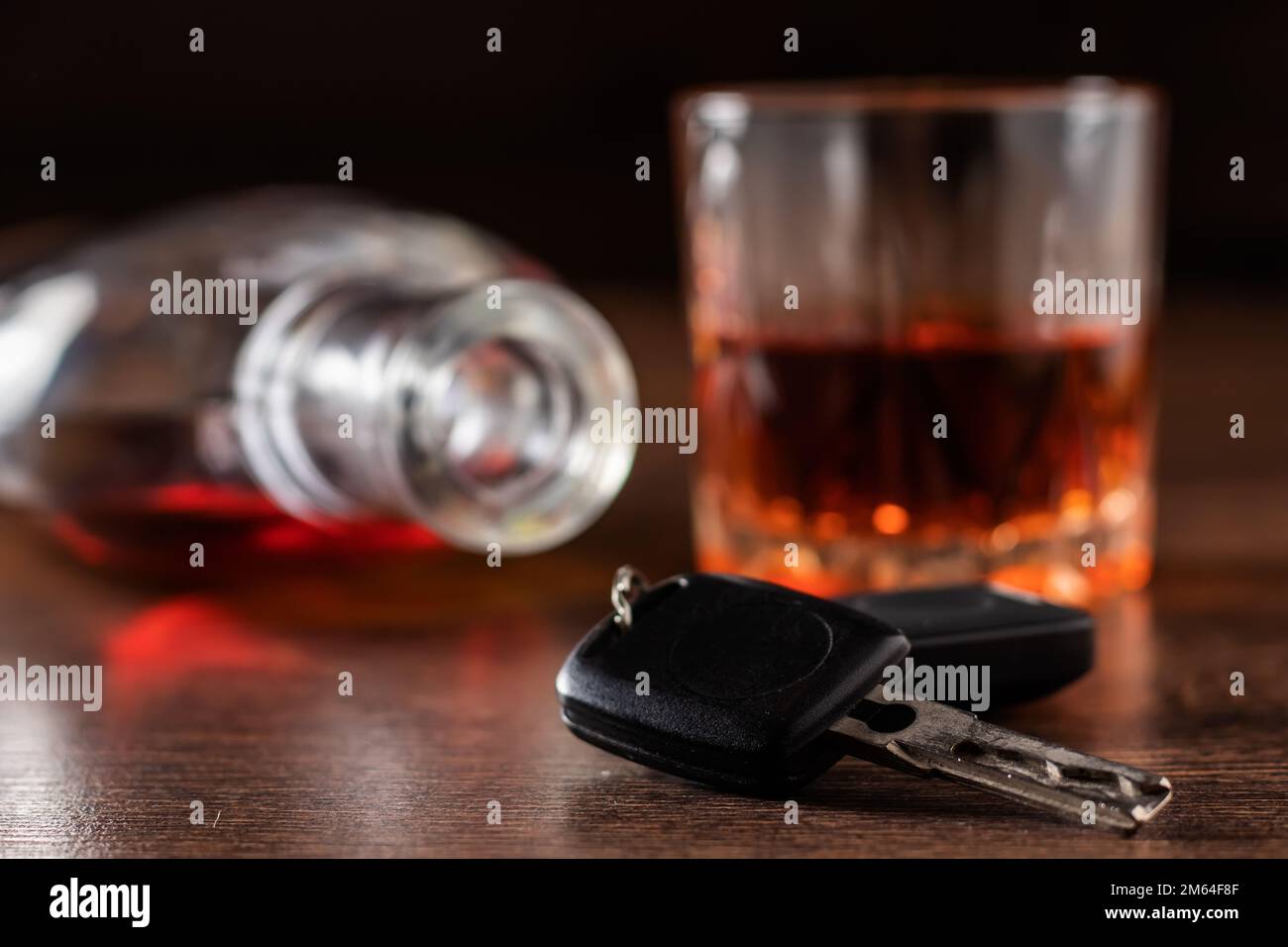 Alcoholic drink in a glass and car keys on a wooden desk. Drunk driving ...