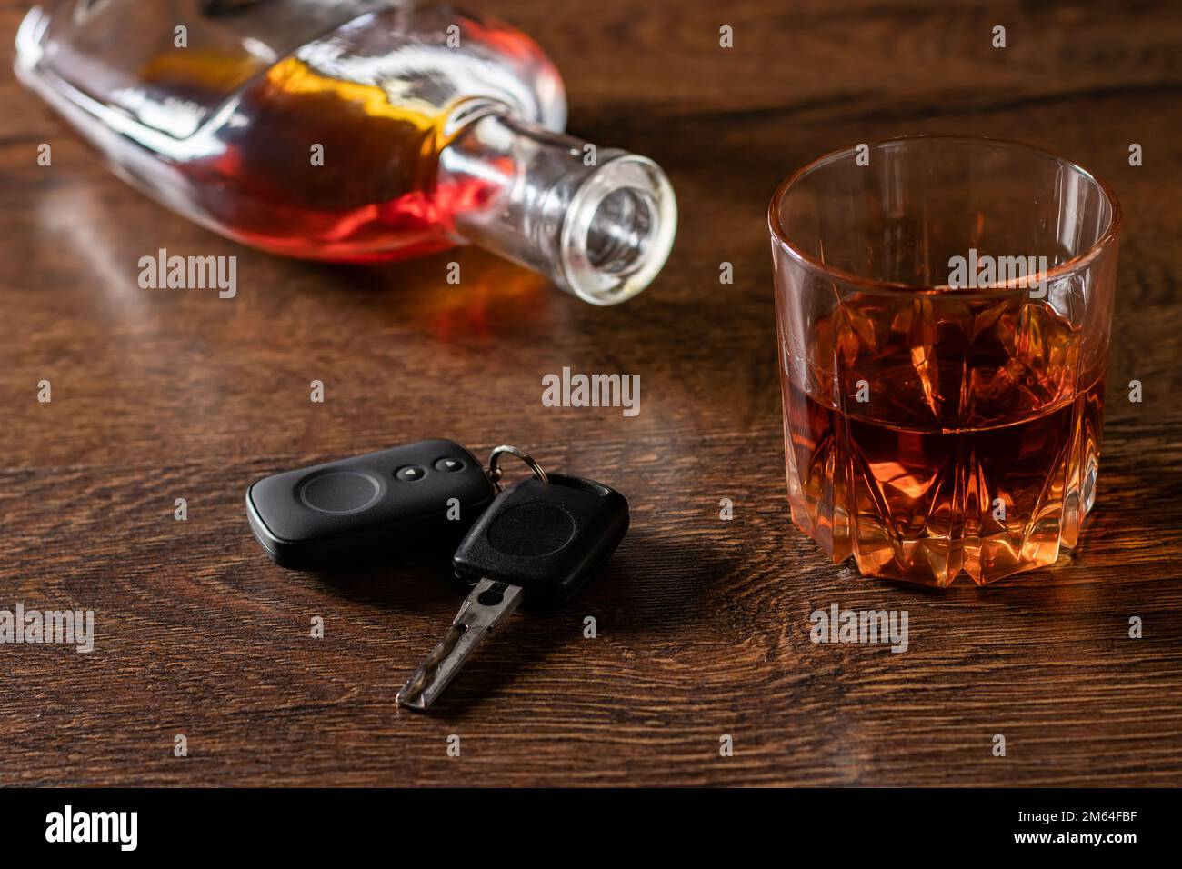Alcoholic drink in a glass and car keys on a wooden desk. Drunk driving ...