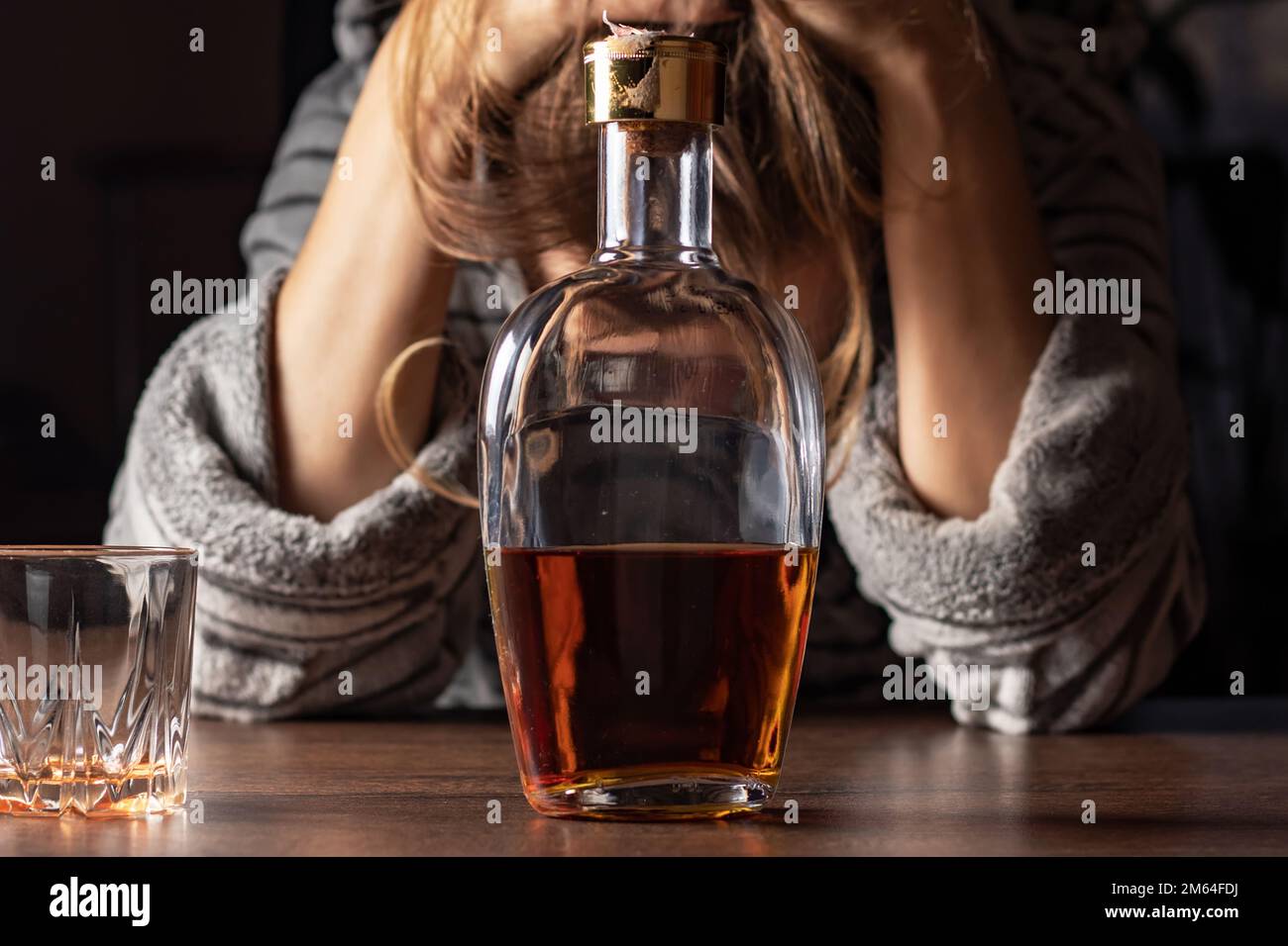 Female alcoholism. Female woman sit to table drink alcohol bottle at ...