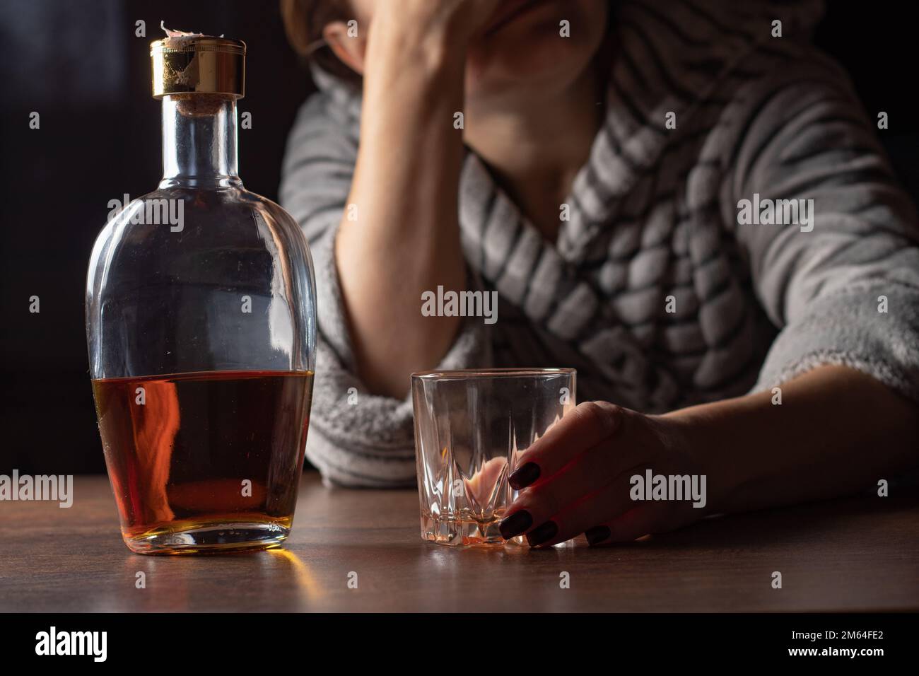 Female alcoholism. Female woman sit to table drink alcohol bottle at ...