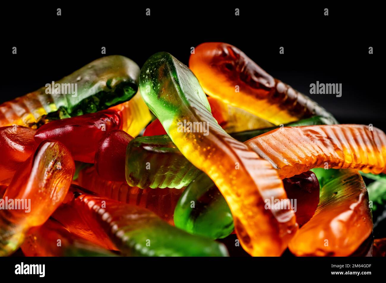Heap juicy colorful jelly worms sweets. Gummy candies. Snakes. On black ...