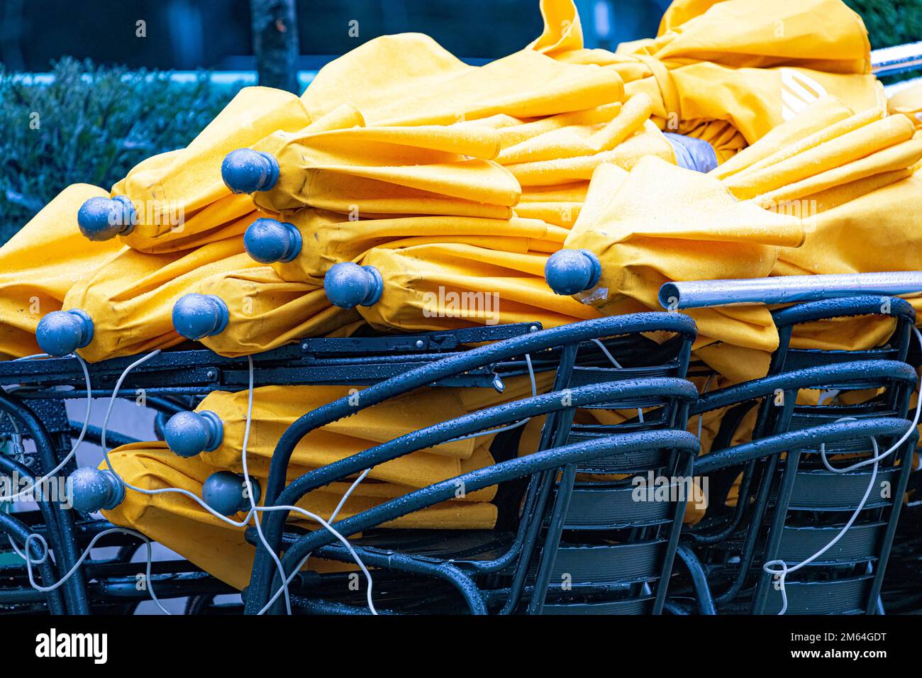 Stacked parasols and chairs during rain Stock Photo - Alamy