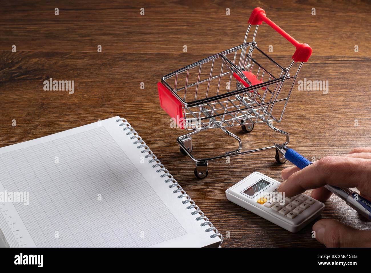 Man calculates the budget. Shopping cart a on table with calculator and ...