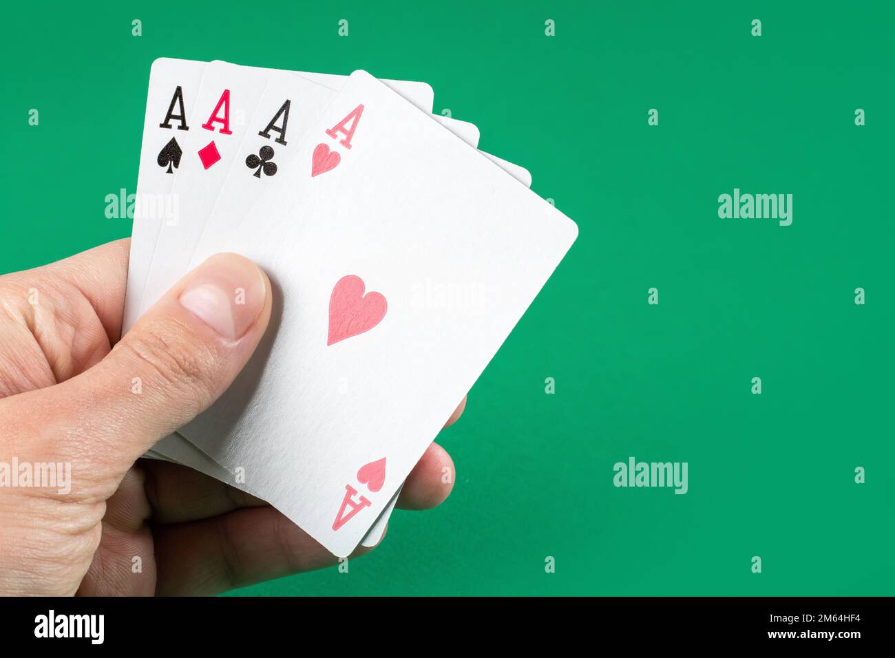 Playing cards in hand on green background Stock Photo - Alamy