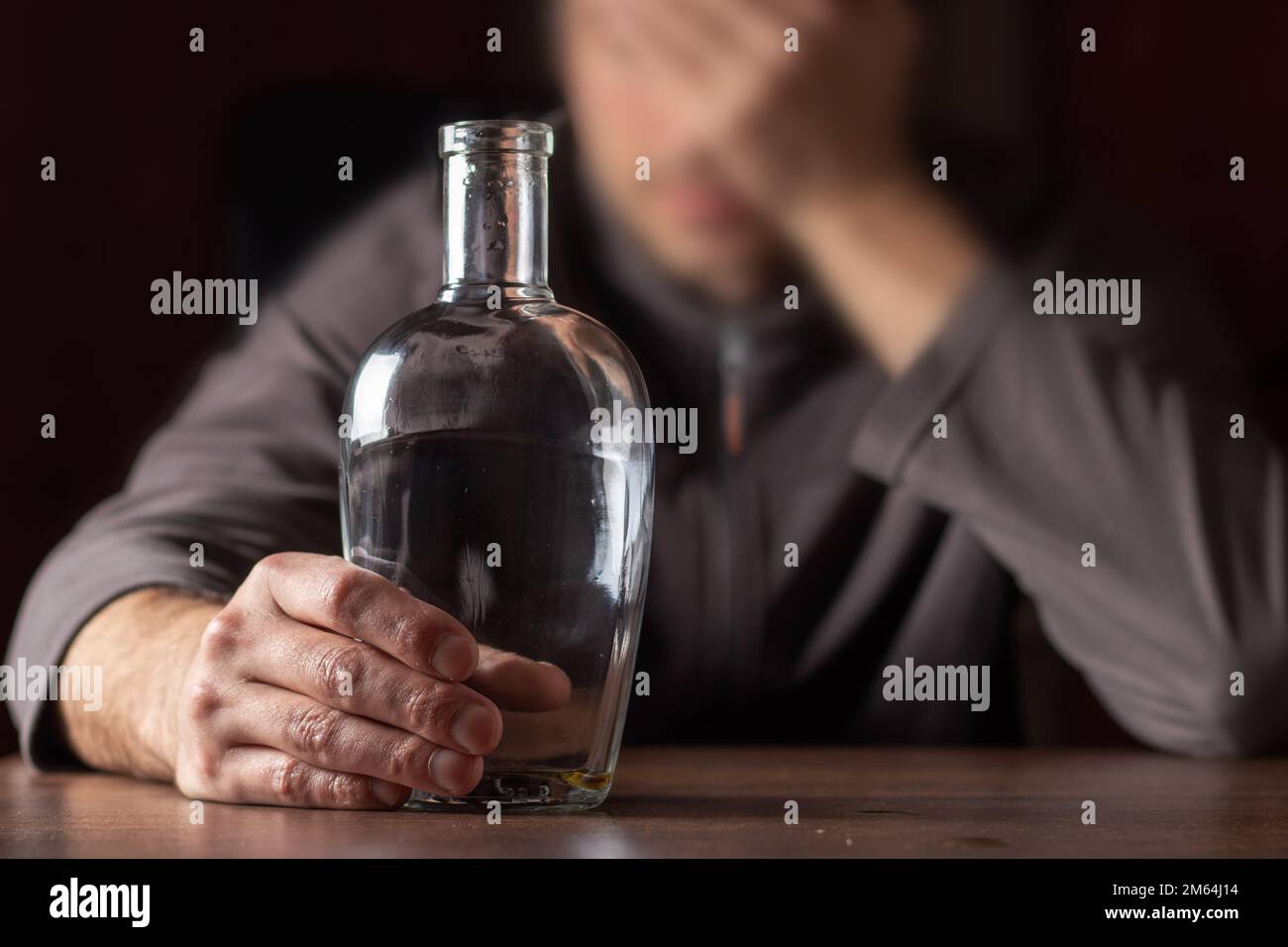 Drunk man holding his head with almost empty bottle of alcohol Stock ...